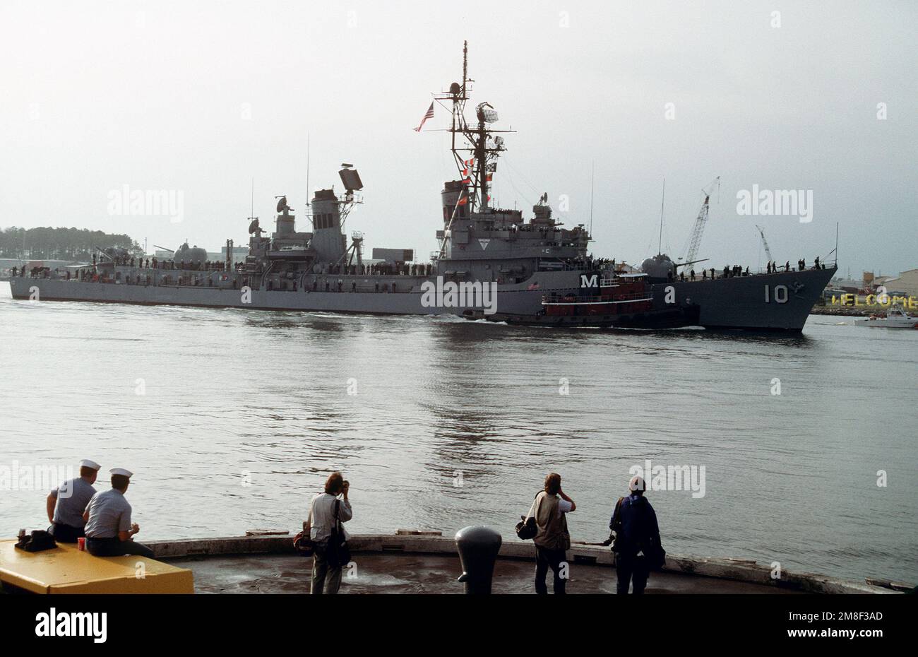 A commercial tug boat accompanies the guided missile destroyer USS ...