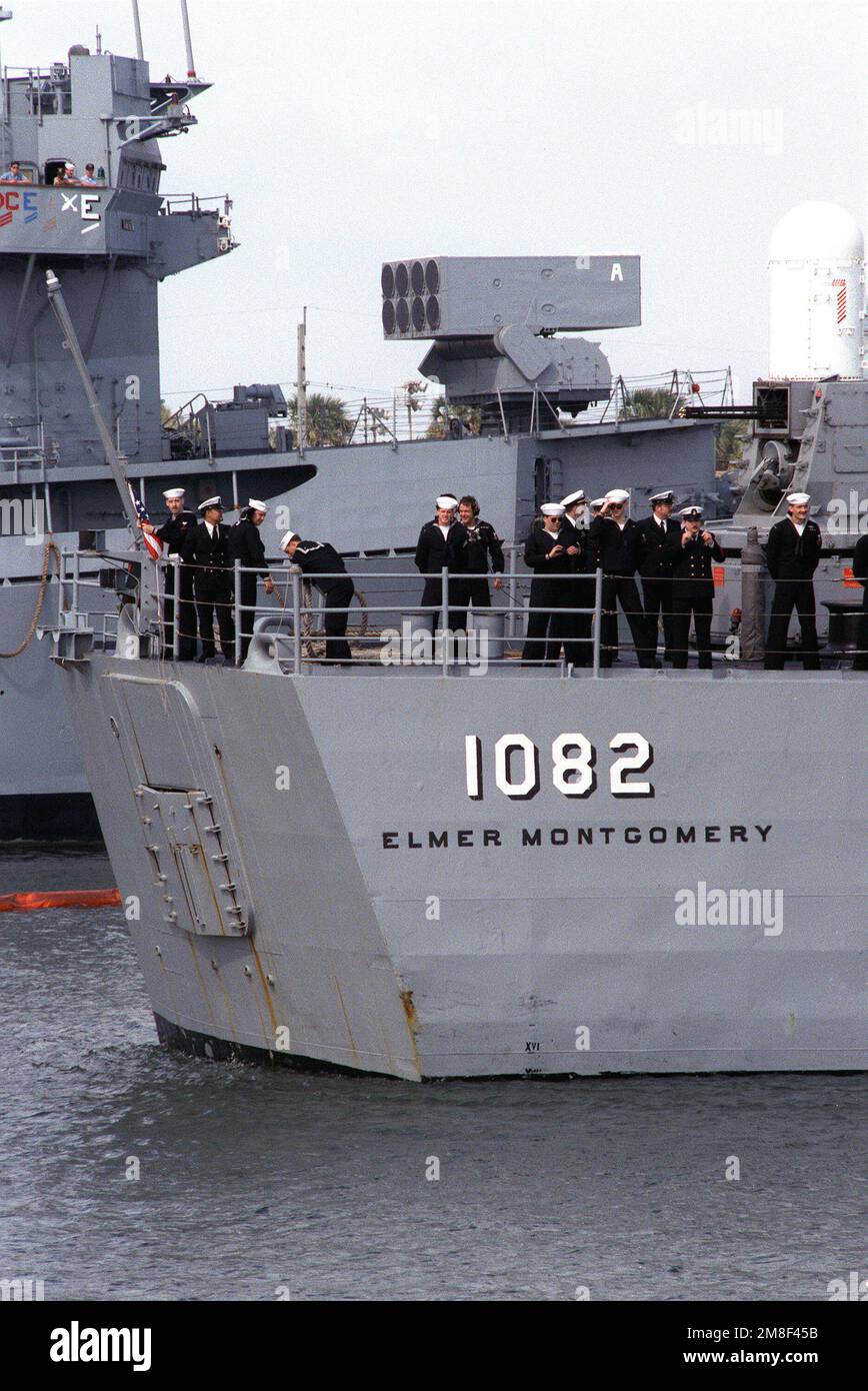 Crew members stand on the stern of the frigate USS ELMER MONTGOMERY (FF ...