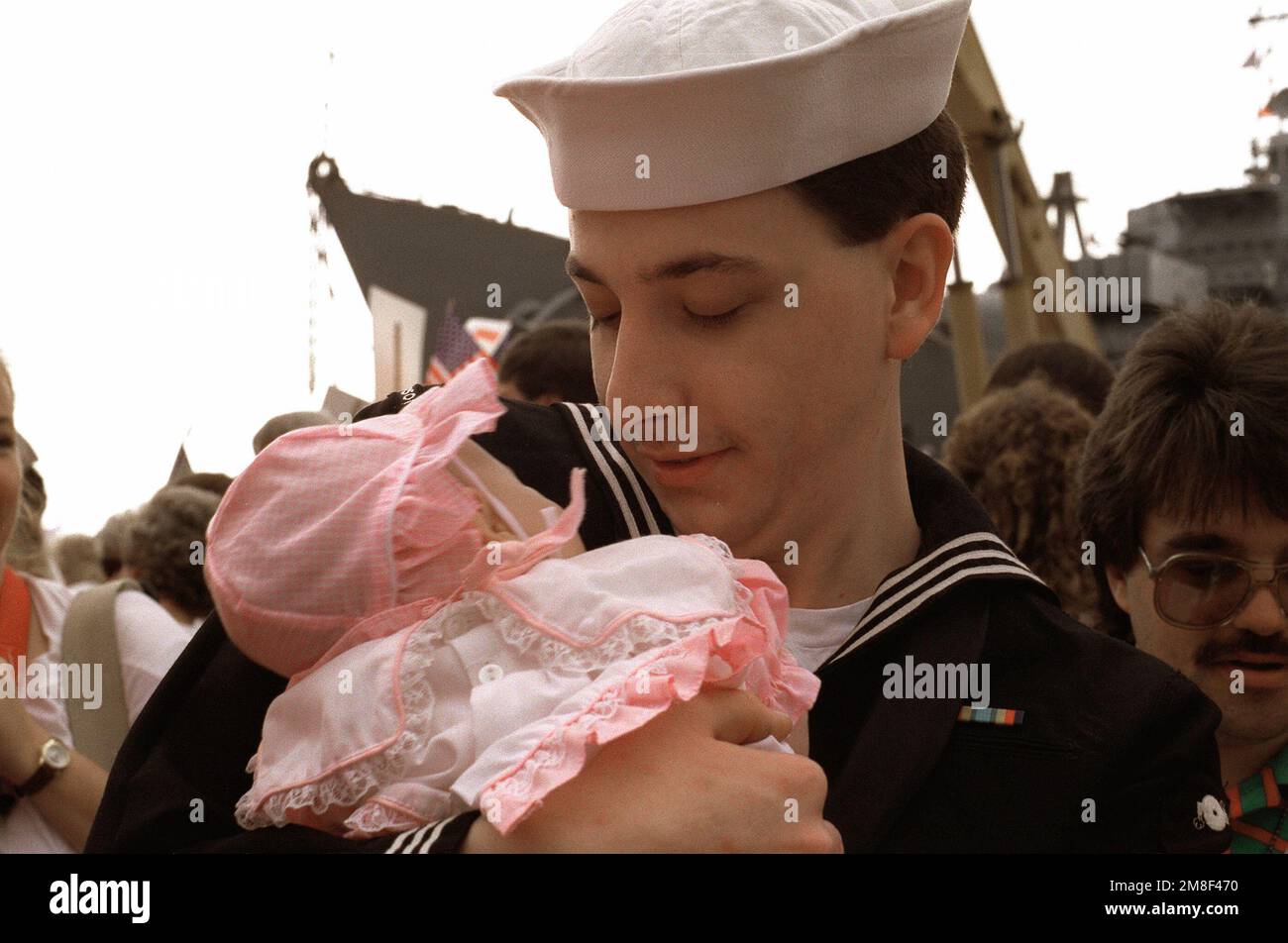 A sailor holds his daughter upon his arrival at the station aboard one ...