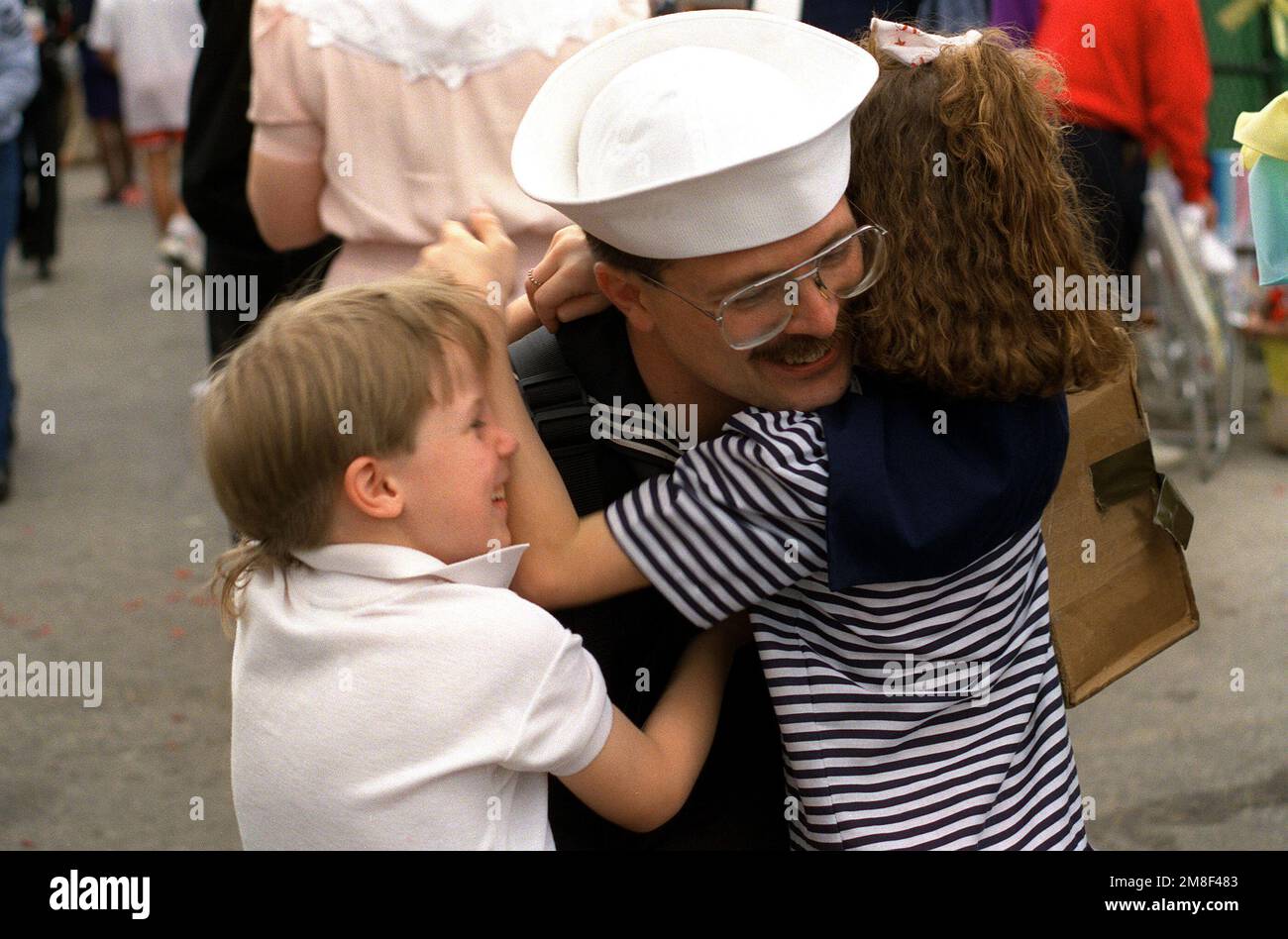 A sailor hugs his children upon his arrival at the station aboard one ...