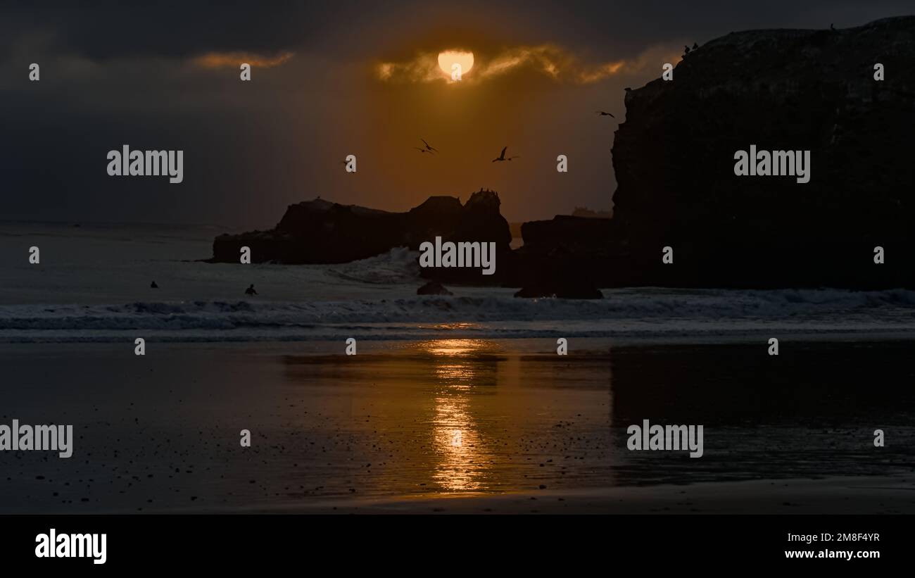 The sun broke though dark cloud on the beach with cliffs Stock Photo ...