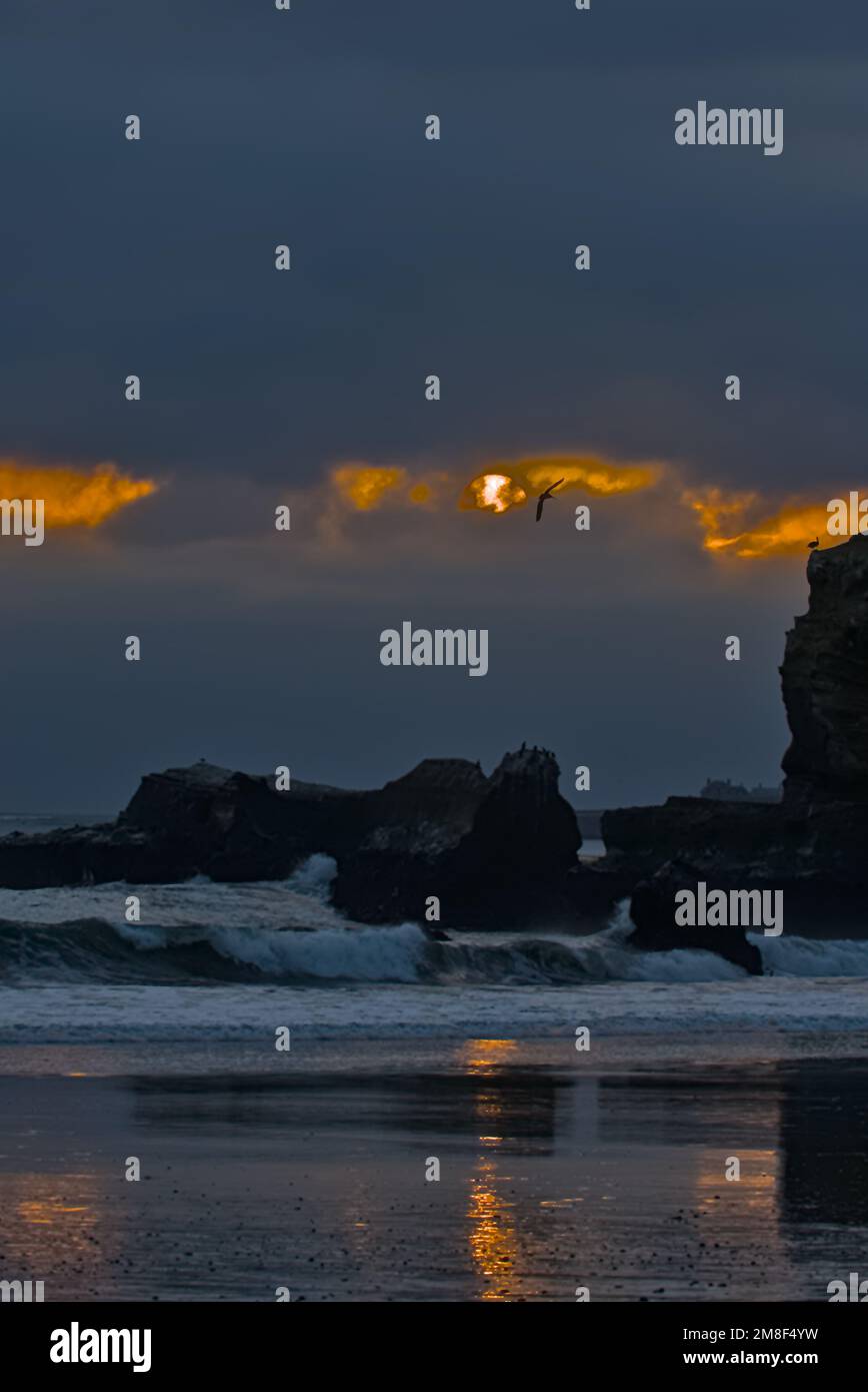 The sun broke though dark cloud on the beach with cliffs Stock Photo ...