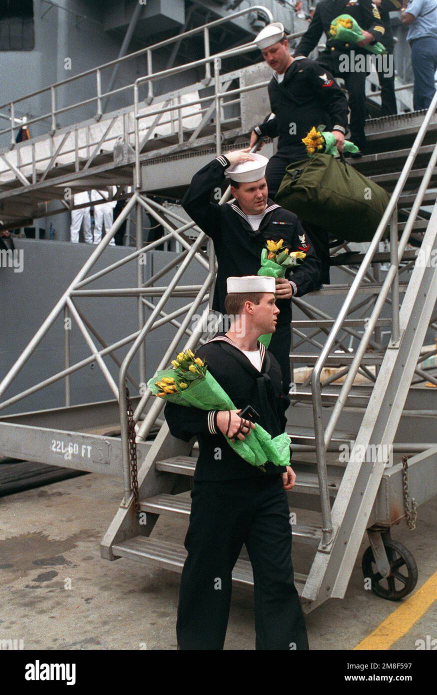 Crew members disembark from the guided missile cruiser USS THOMAS S ...