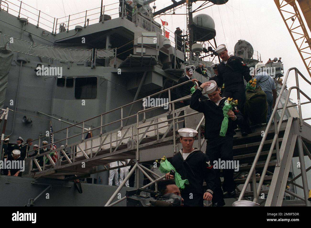 Crew members disembark from the guided missile cruiser USS THOMAS S ...