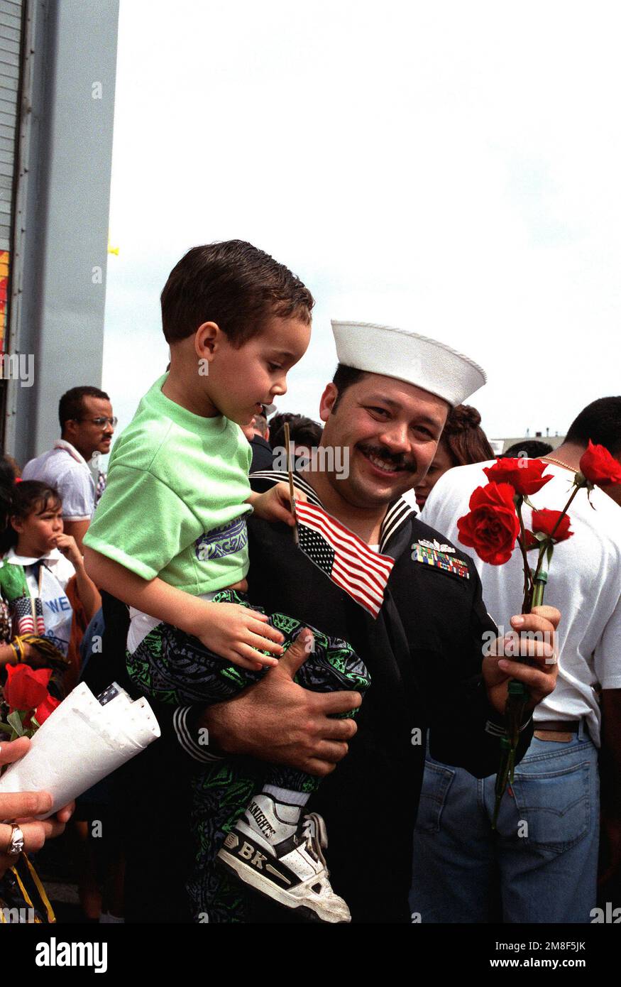 A petty officer holds his son and several roses as he is reunited with ...