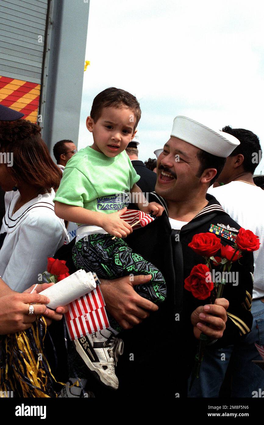 A petty officer holds his son and several roses as he is reunited with ...