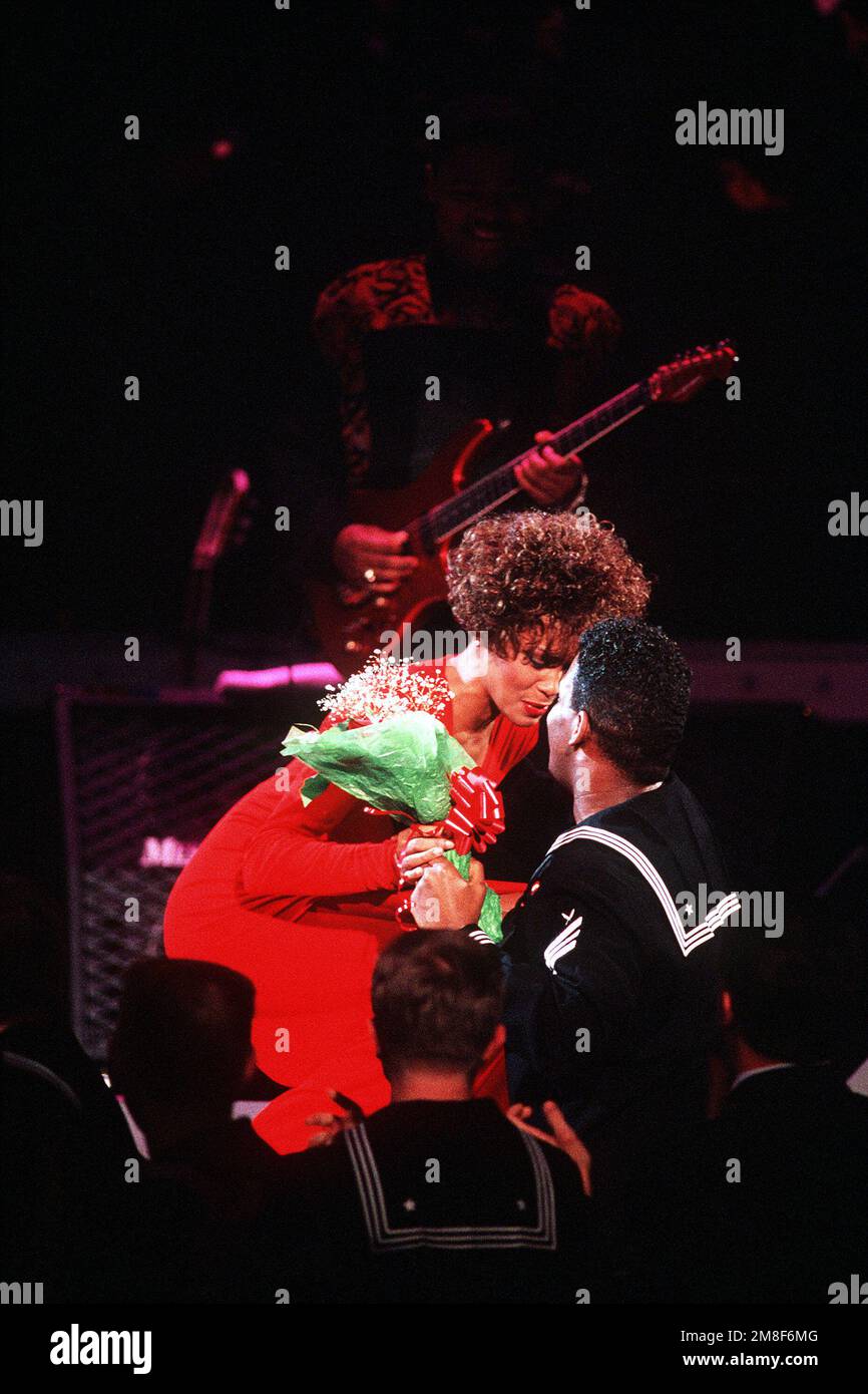 Singer Whitney Houston accepts flowers from a fan as she performs ...