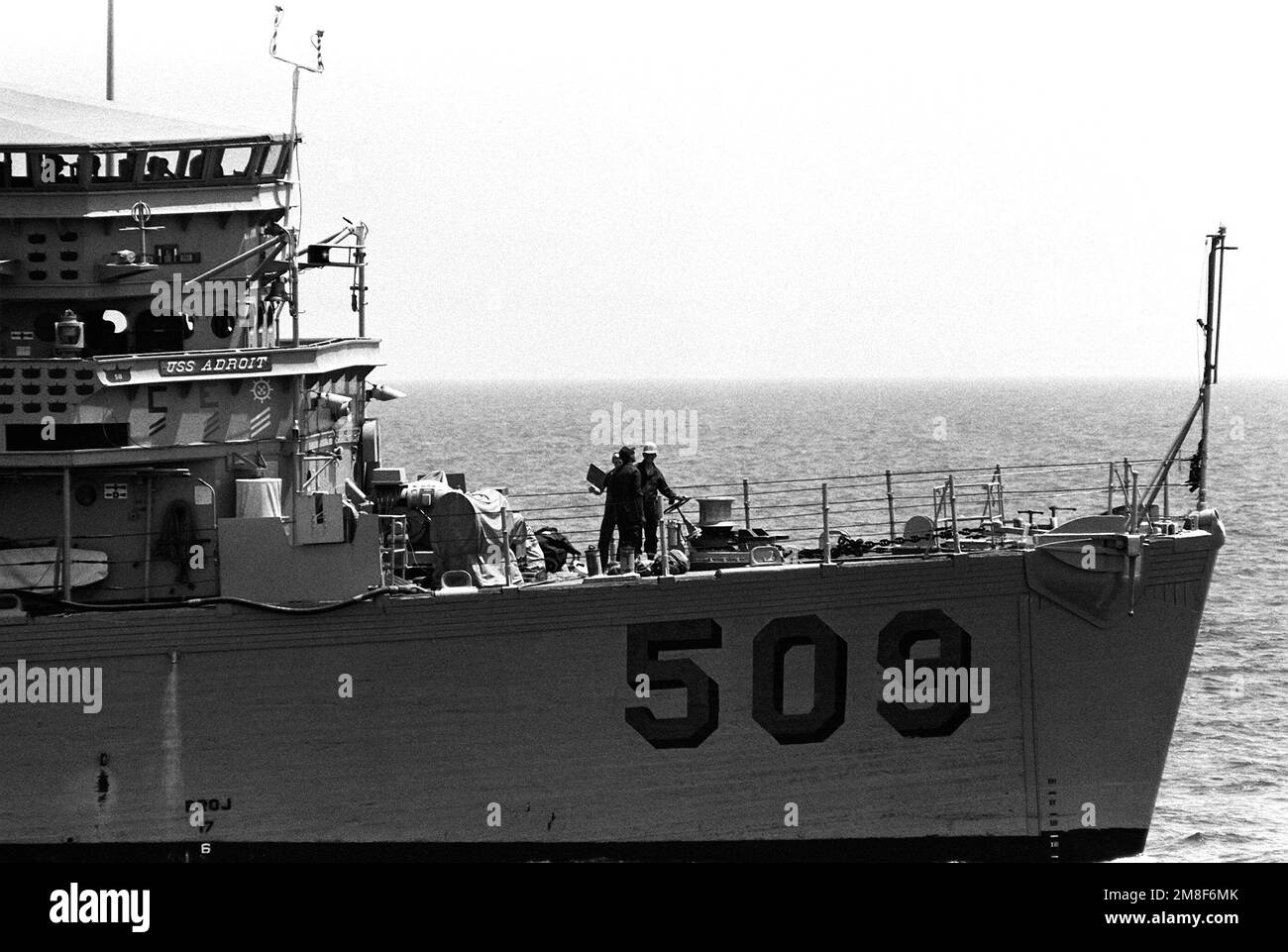 Crewmen on the deck of the ocean minesweeper USS ADROIT (MSO-509) stand ...
