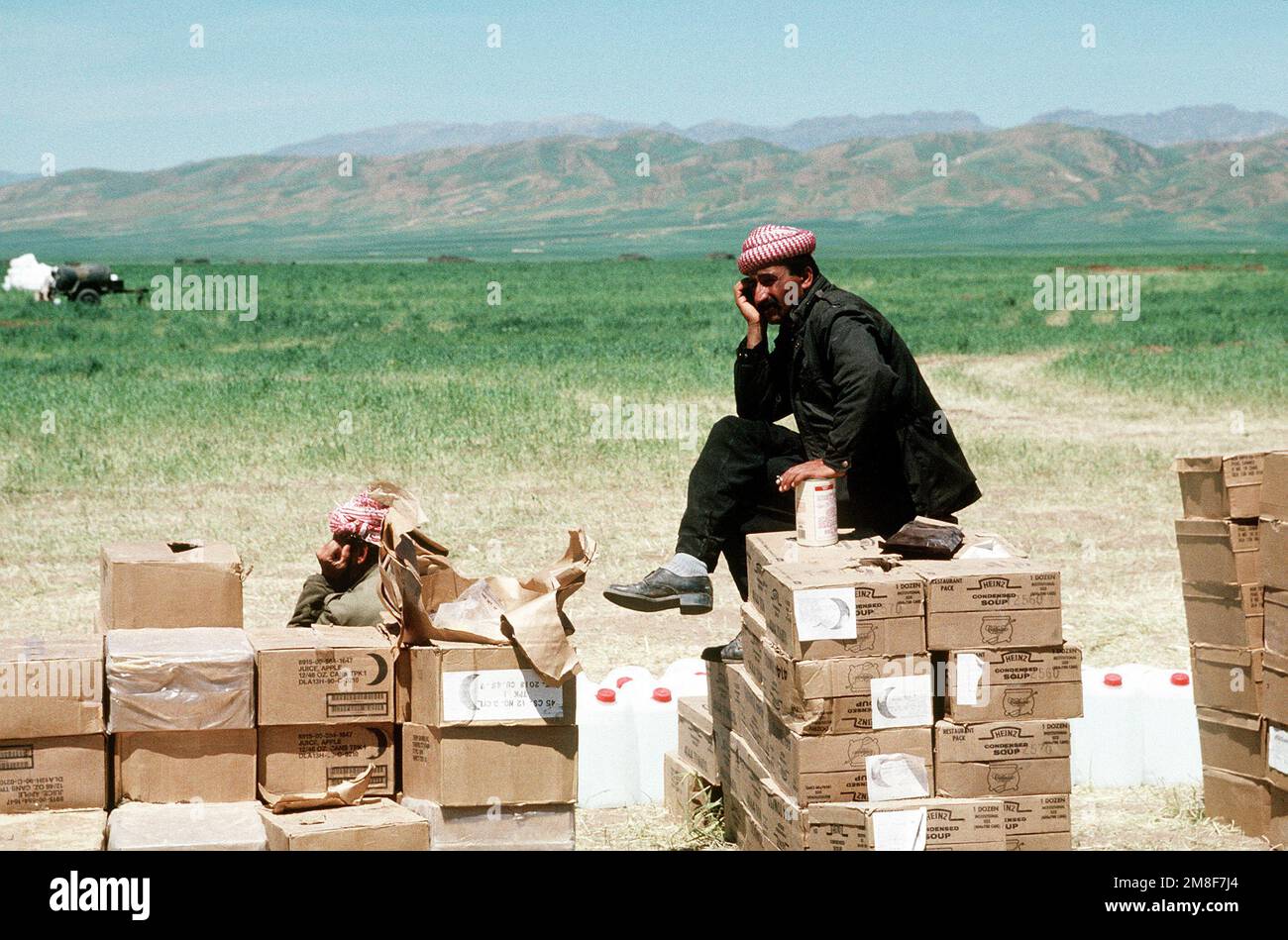 A Kurdish refugee sits atop a stack of supplies on the outskirts of the ...