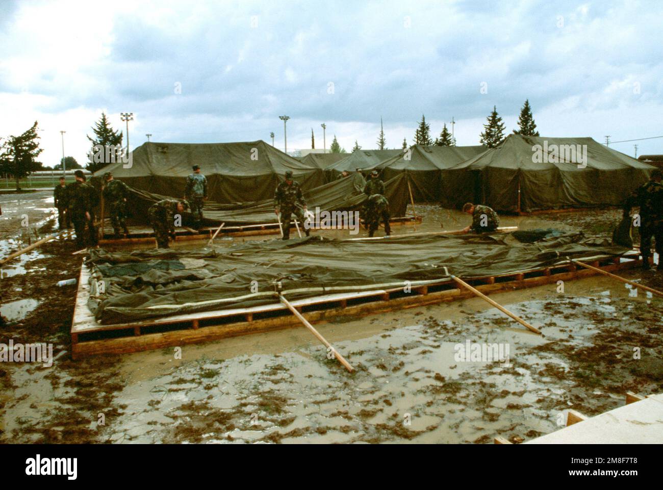 U.S. Air Force and Army personnel wade through mud to raise tents on ...