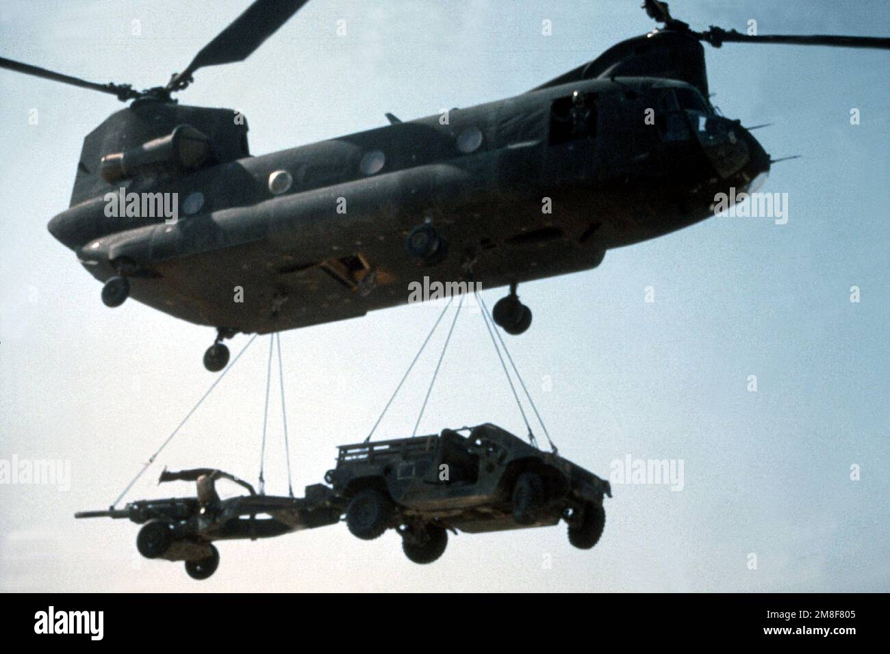 A CH-47 Chinook helicopter lifts an M102 105mm towed howitzer and an M998 High-Mobility ...