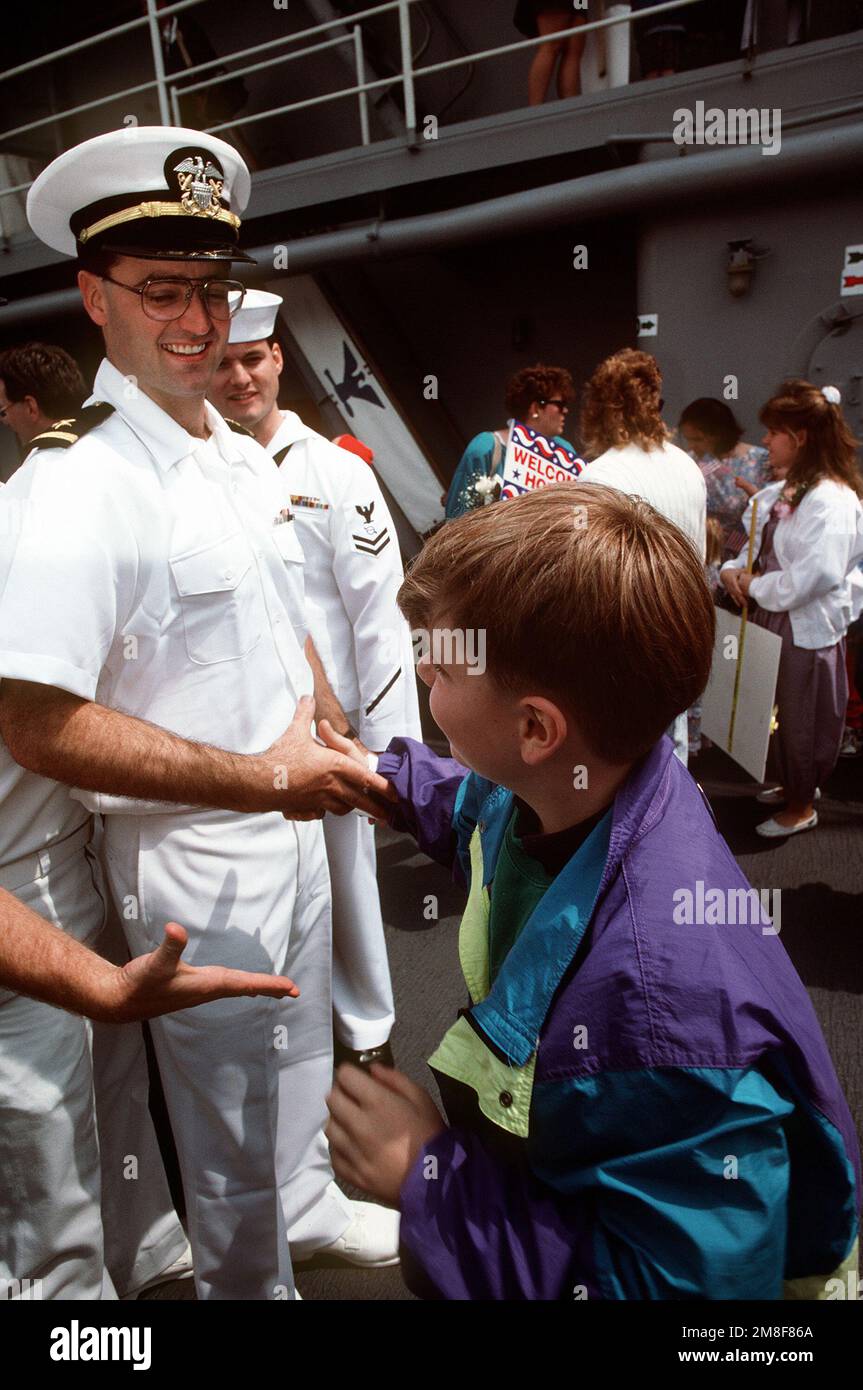 A boy shakes hands with crew members from the replenishment oiler USS ...