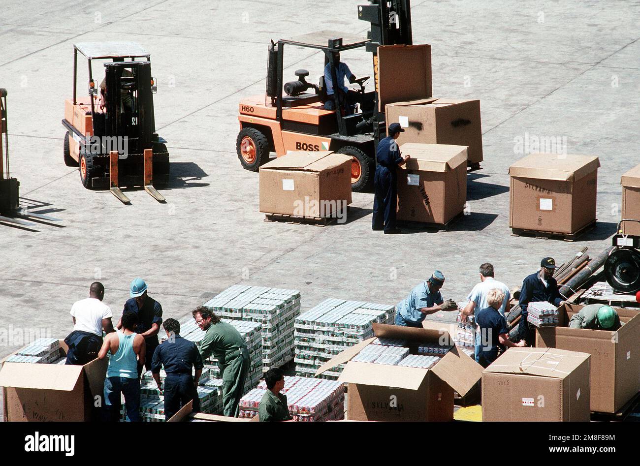 Dock workers and U.S. Navy supply personnel palletize cases of soft ...