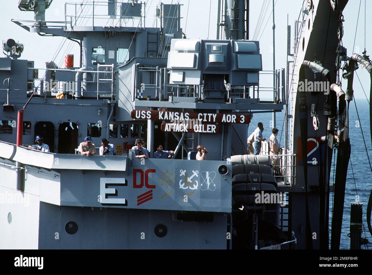 Officers and crewmen stand on a bridge wing aboard the replenishment ...