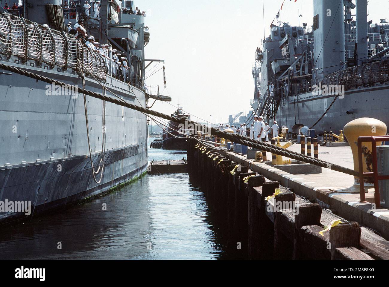 Sailors stand at the railing aboard the tank landing ship USS ...