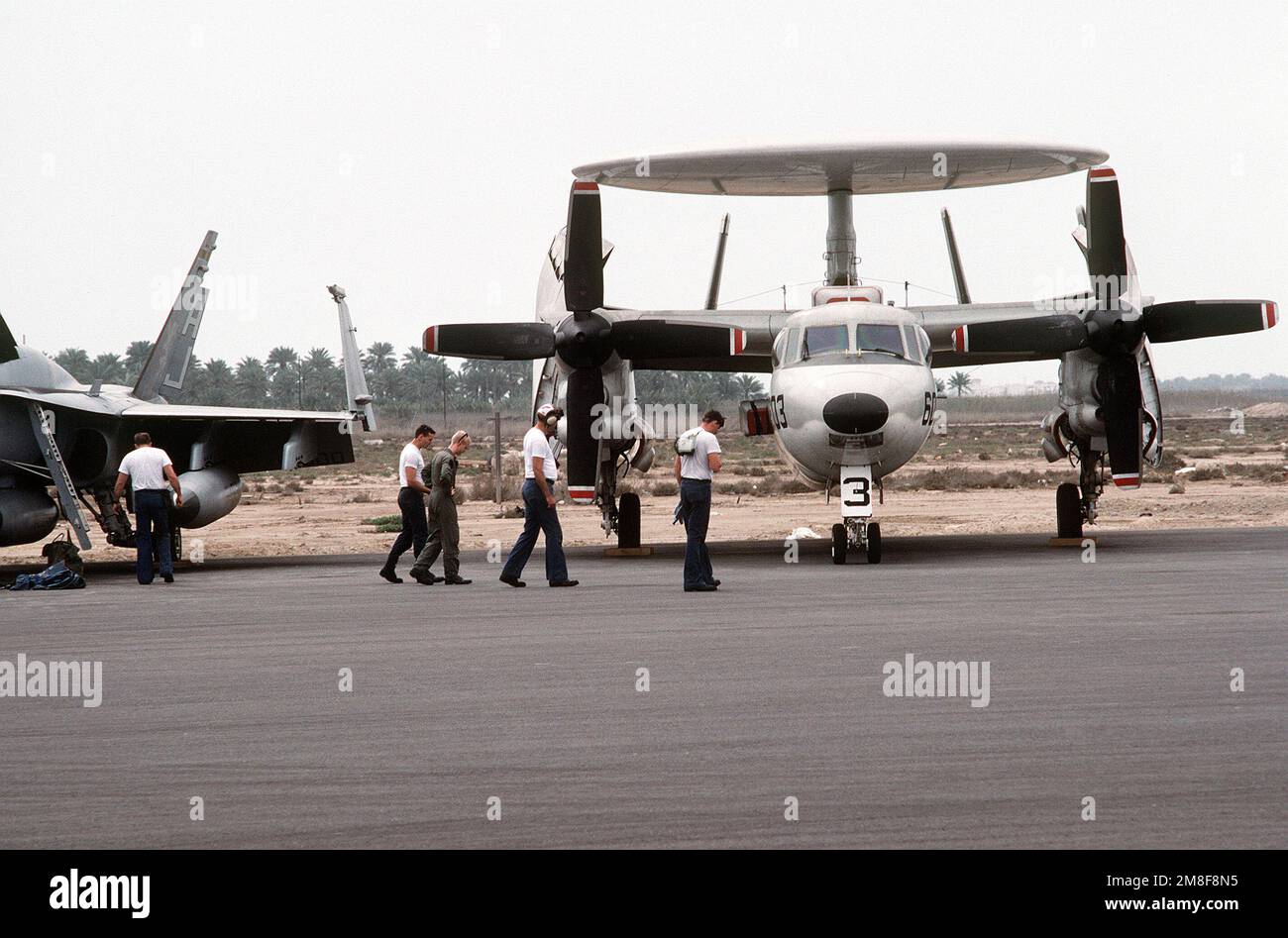 Sailors walk past an E-2C Hawkeye airborne early warning and control ...
