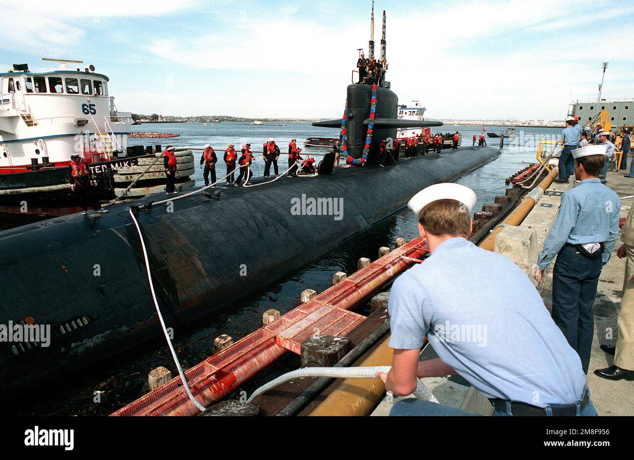 Line handlers on shore and aboard the nuclear-powered attack submarine ...