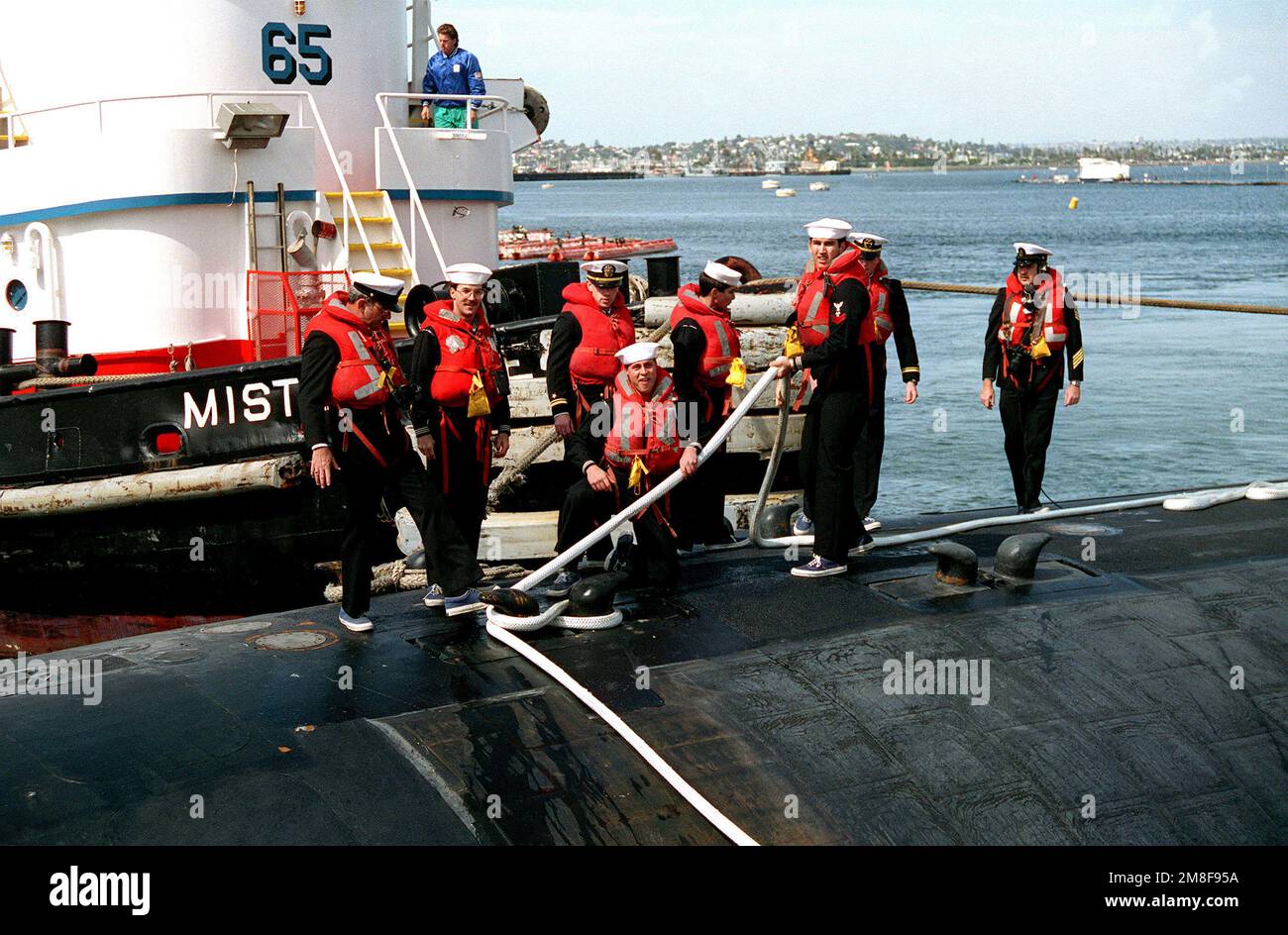 Line handlers stand by aboard the nuclear-powered attack submarine USS ...