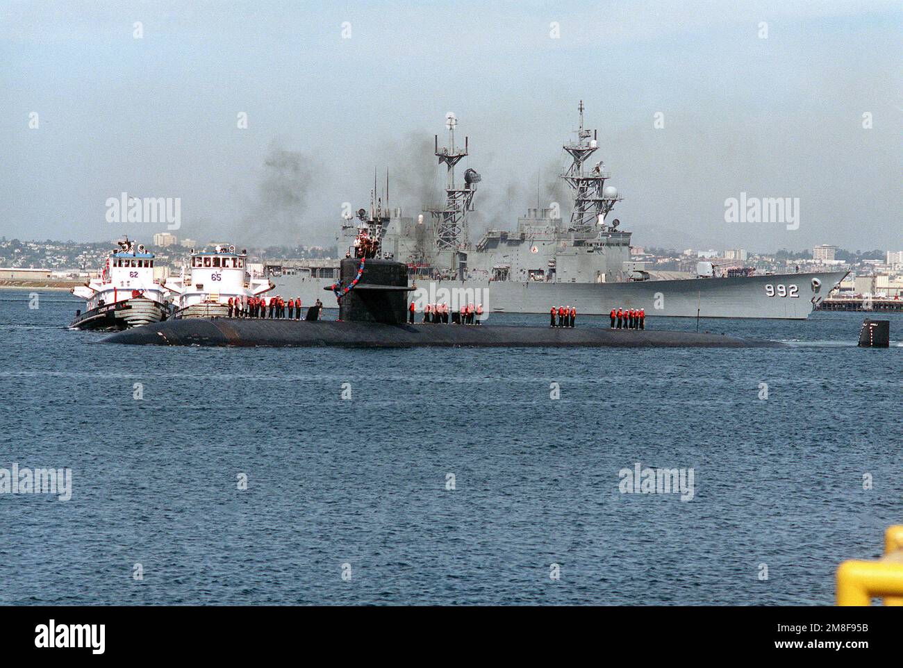 Two commercial tug boats maneuver the nuclear-powered attack submarine ...