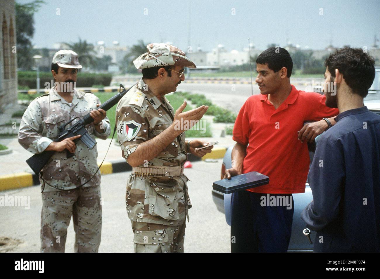 An officer of the Kuwaiti police force speaks with local residents as ...