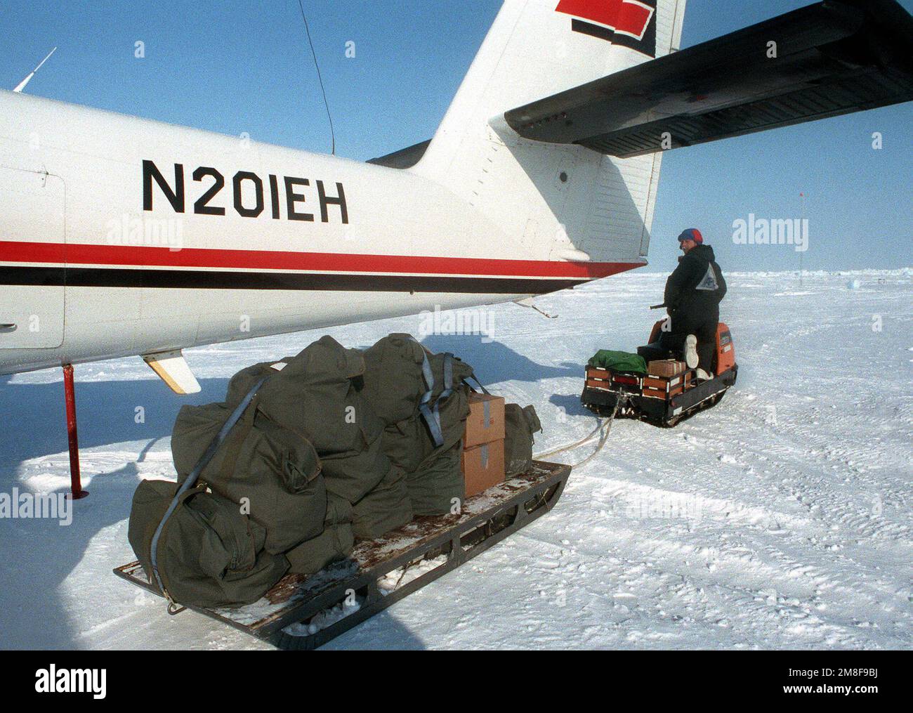 A man on a snowmobile prepares to pull a sled loaded with supplies to ...