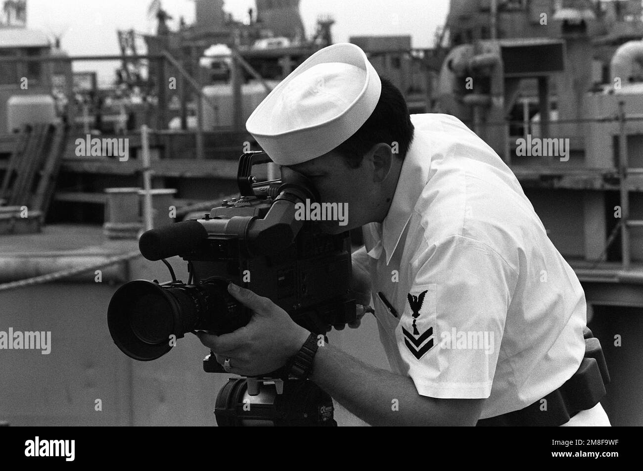 A photographer's mate prepares to film ships returning to the station ...