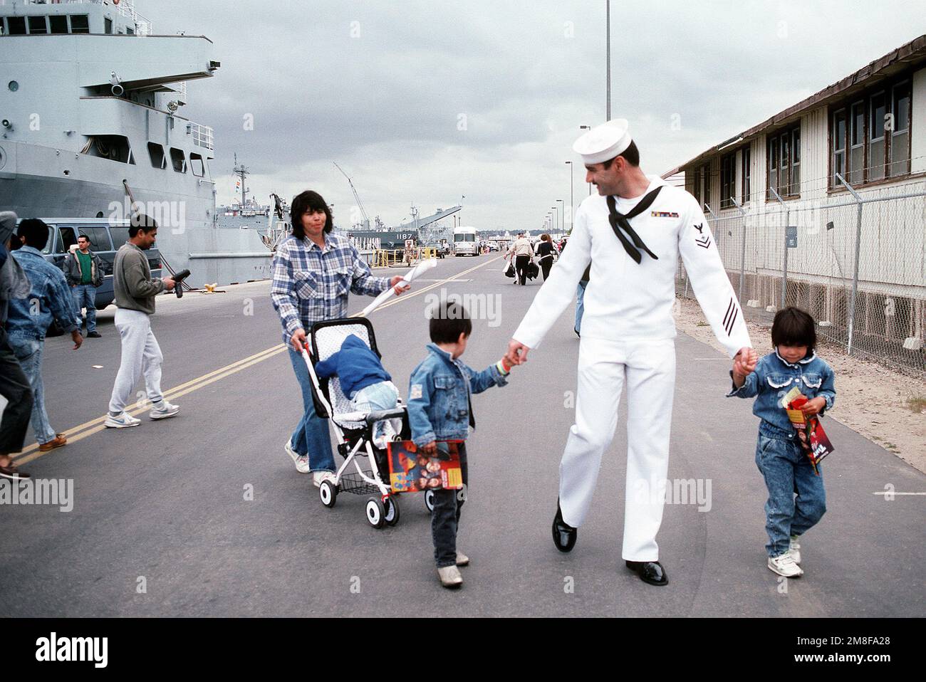 A petty officer walks across a street with his family after ...