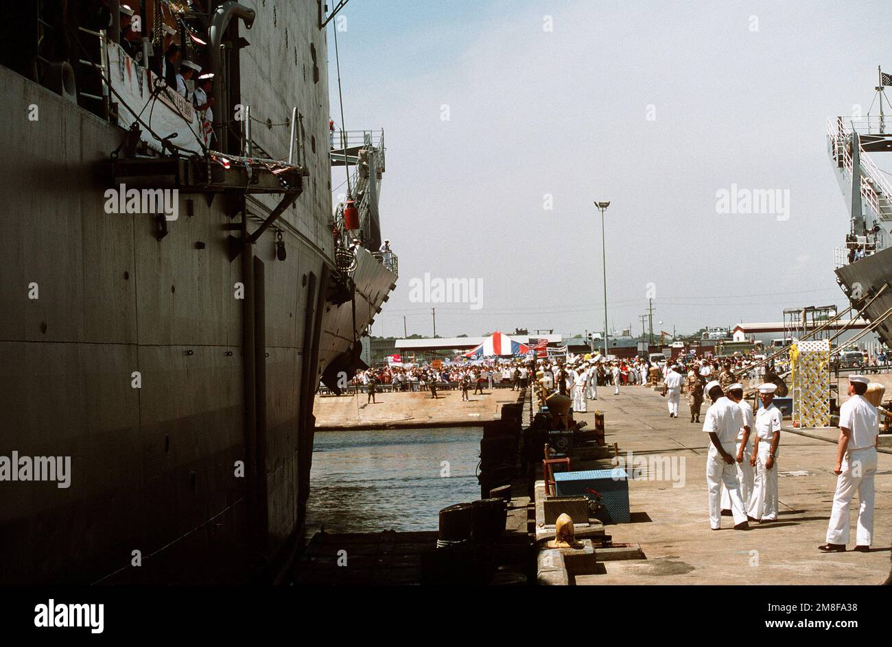 Line handlers stand by on the pier as the tank landing ship USS ...
