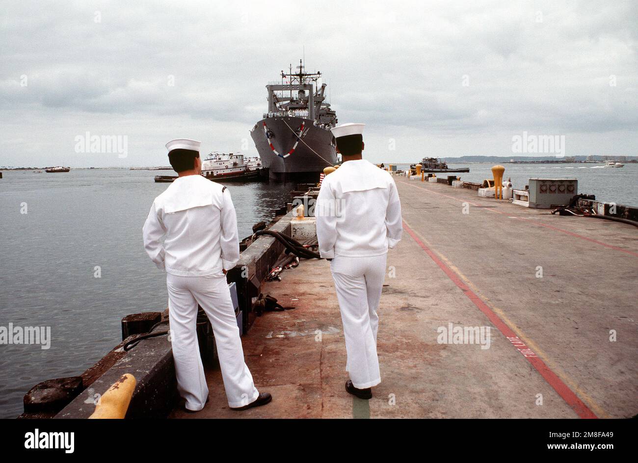 Sailors watch as a commercial harbor tug prepares to pull away from the ...