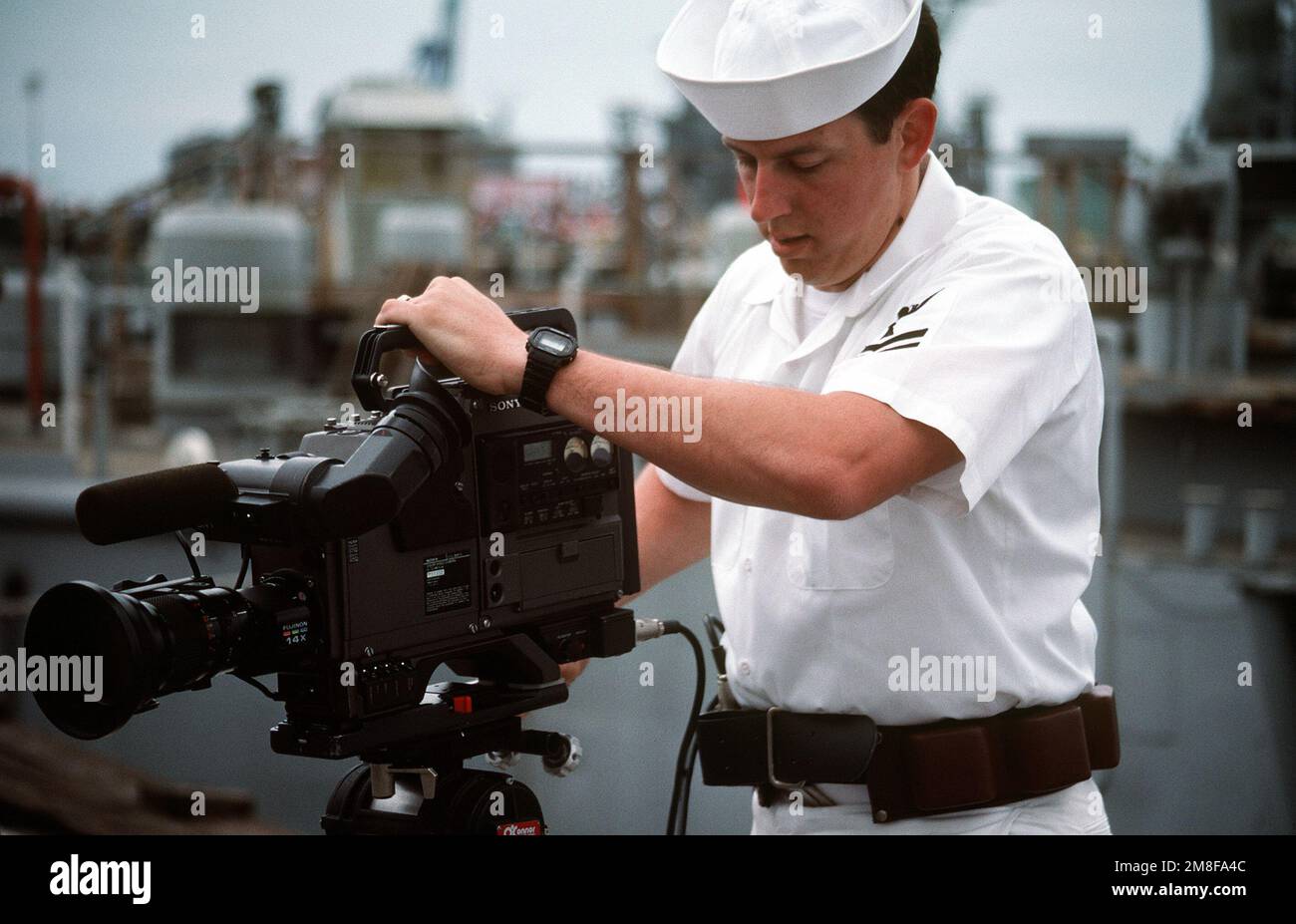 A sailor sets up a videocamera to film the homecoming of the amphibious ...