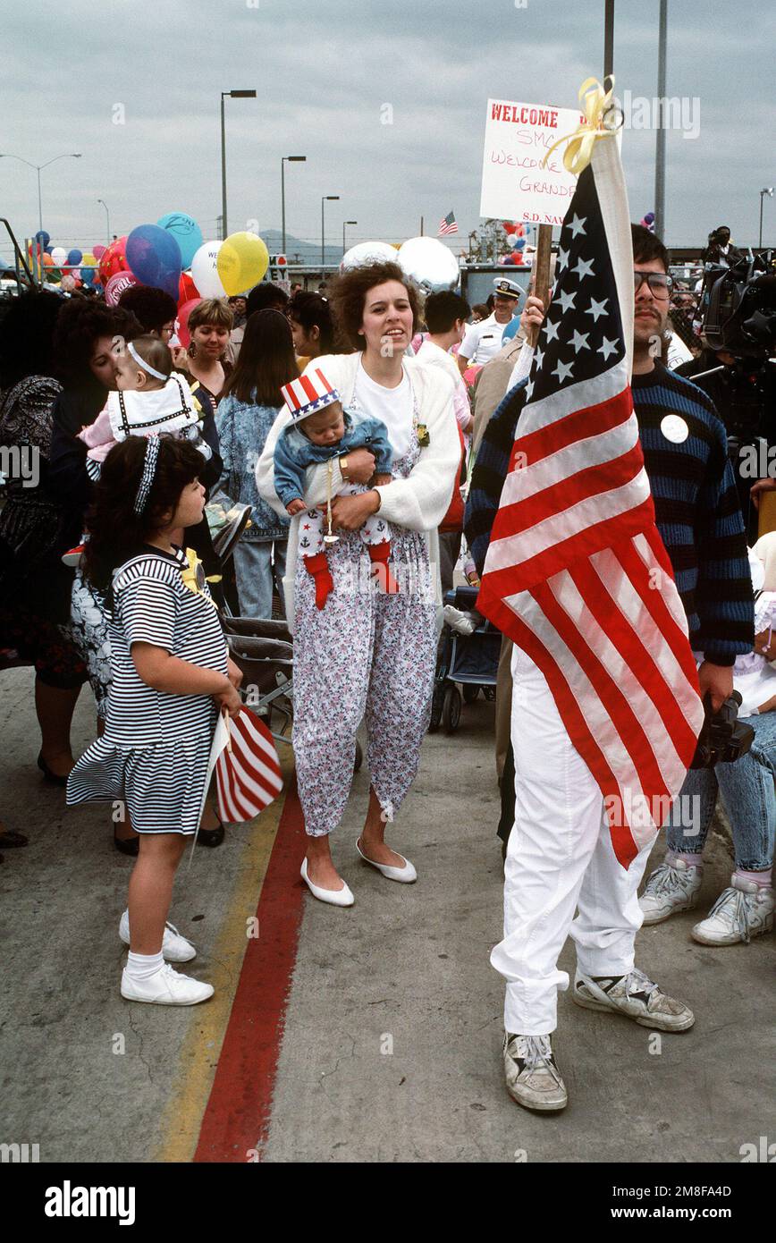 A mother holds her son as she waits for the arrival of her husband, a ...