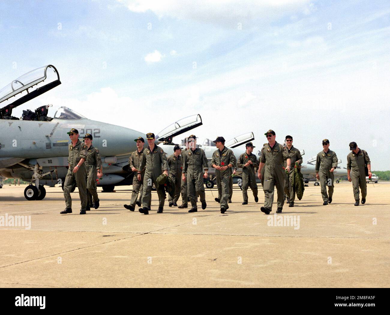 Pilots of Fighter Squadron 33 (VF-33) walk in front of their F-14A ...