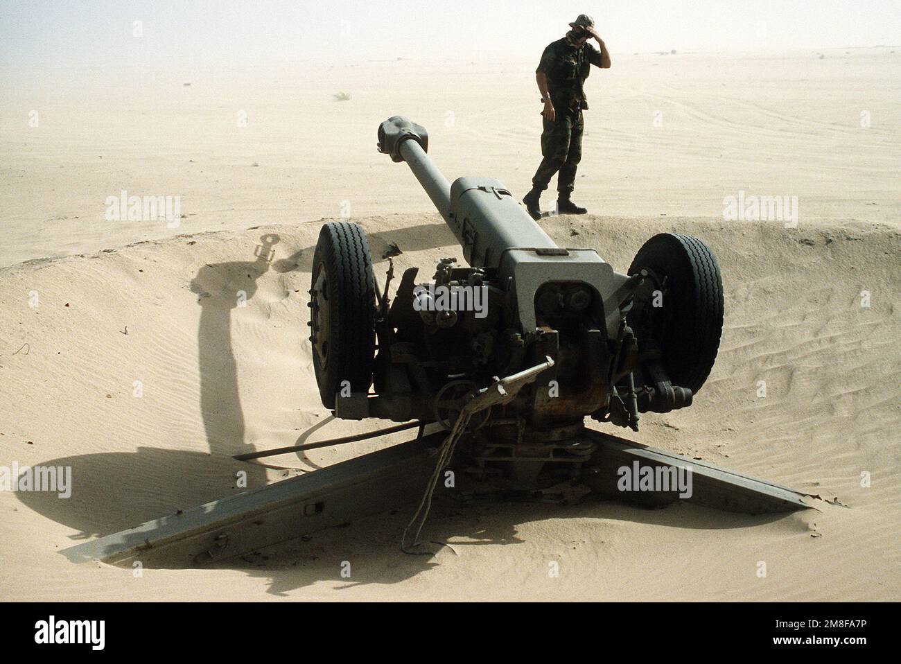 A U.S. soldier inspects and Iraqi D-30 122mm howitzer abandoned near ...