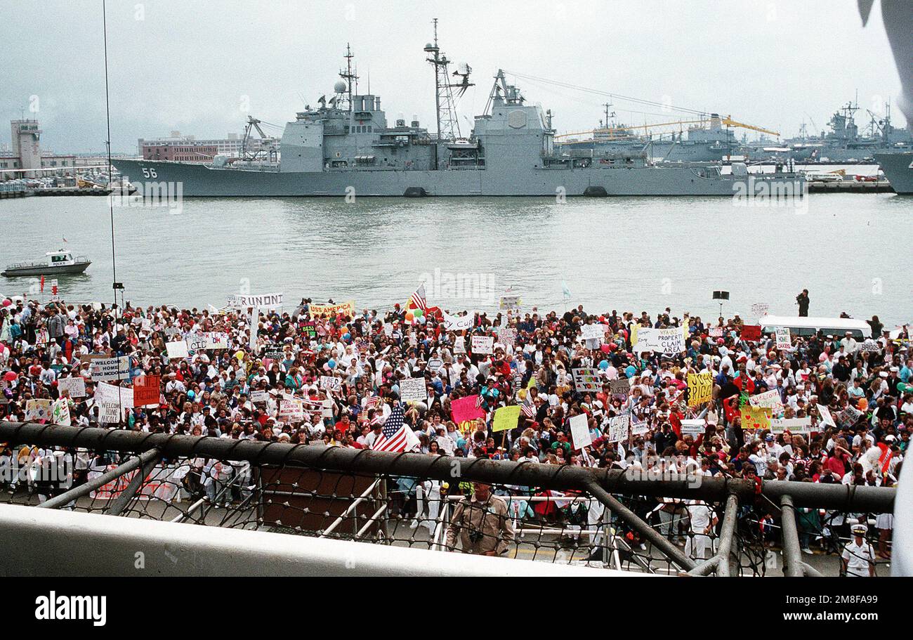 A crowd holds up banners to welcome home crew members aboard the ...