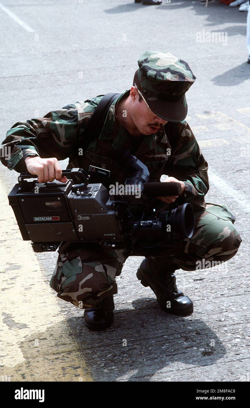 A Navy cameraman adjusts his video camera while covering the arrival of ...