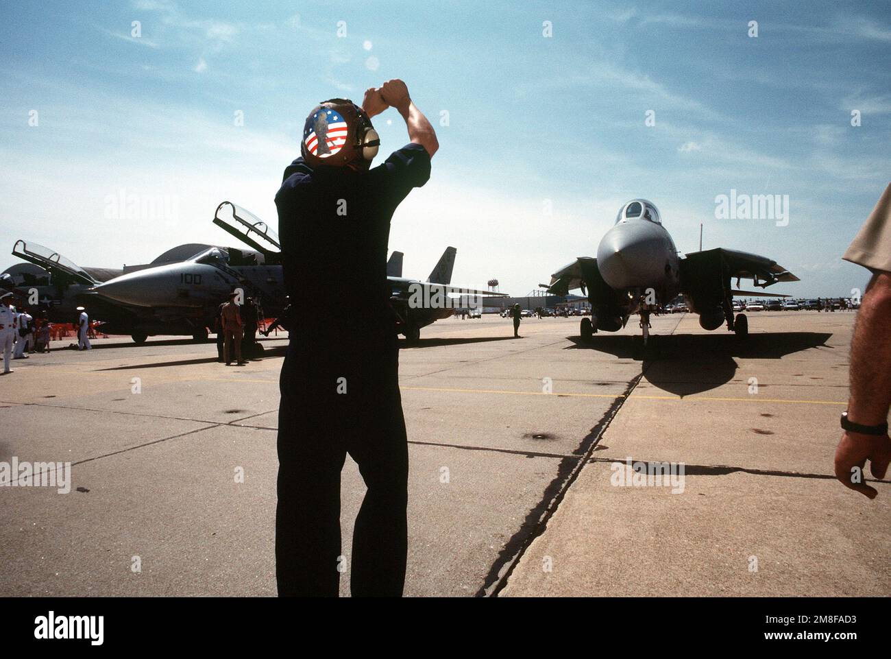 A ground guide signals to the pilot of a Fighter Squadron 102 (VF-102 ...