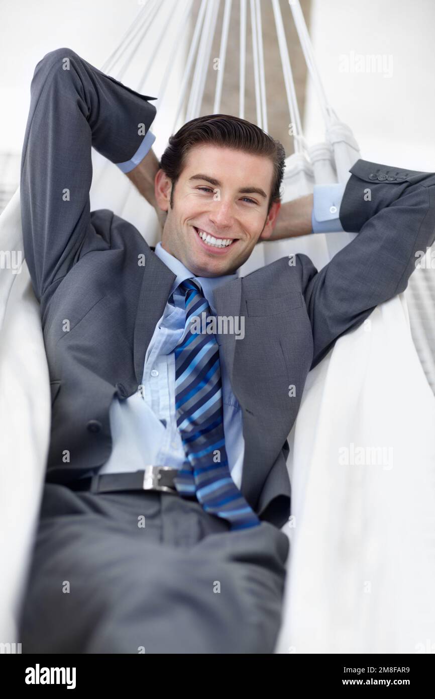 Relaxed approach to business. A young businessman lying on a hammock ...