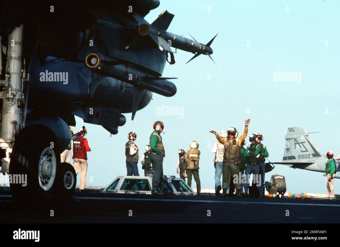 A plane handler guides an F-14A Tomcat aircraft as it taxis toward one ...