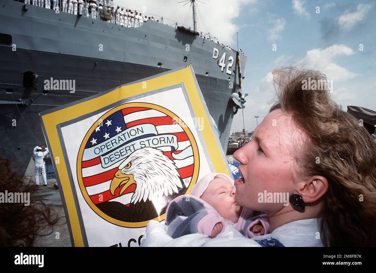 A woman holds her newborn baby as she waits for the destroyer tender ...