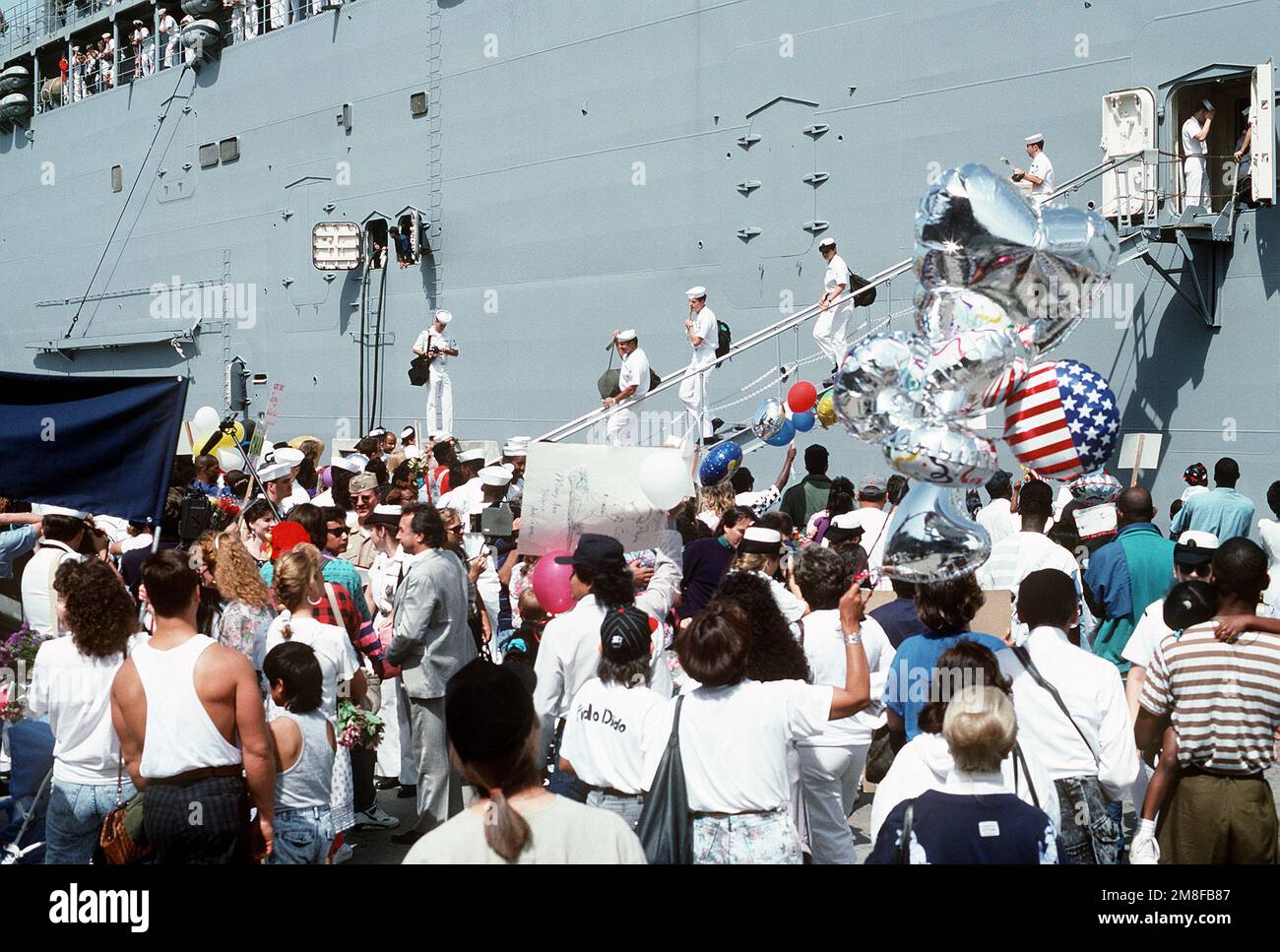 A crowd of family and friends stands on the pier as crew members ...