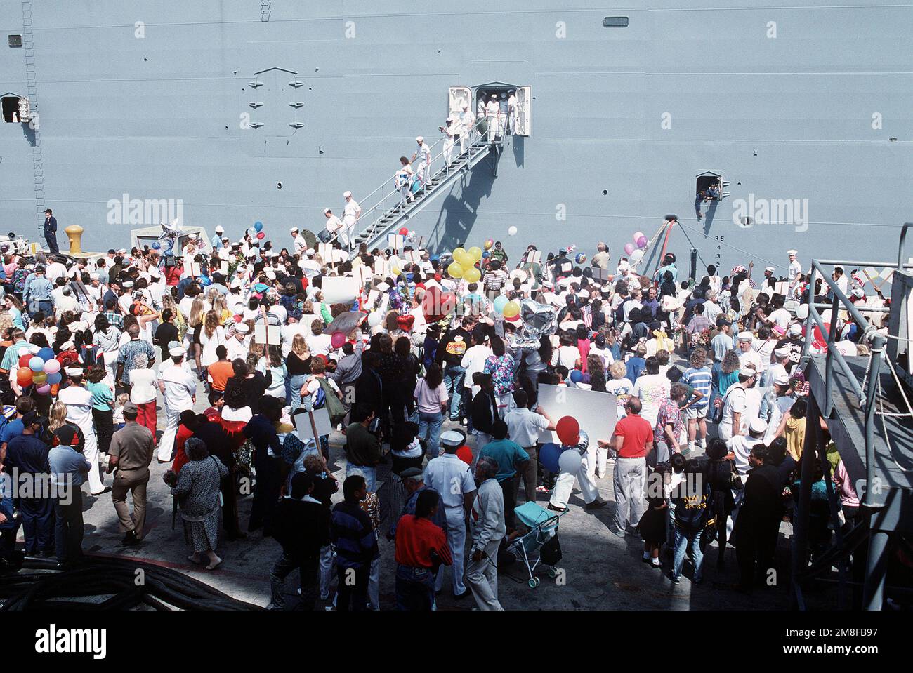 A crowd of family and friends stands on the pier as crew members ...