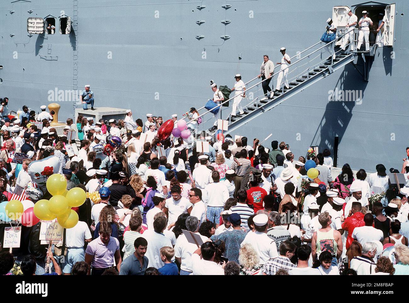 A large crowd waits on the pier as sailors assigned to the destroyer ...