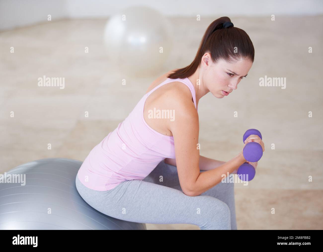Concentrating on her workout. Profile shot of a young woman lifting a ...