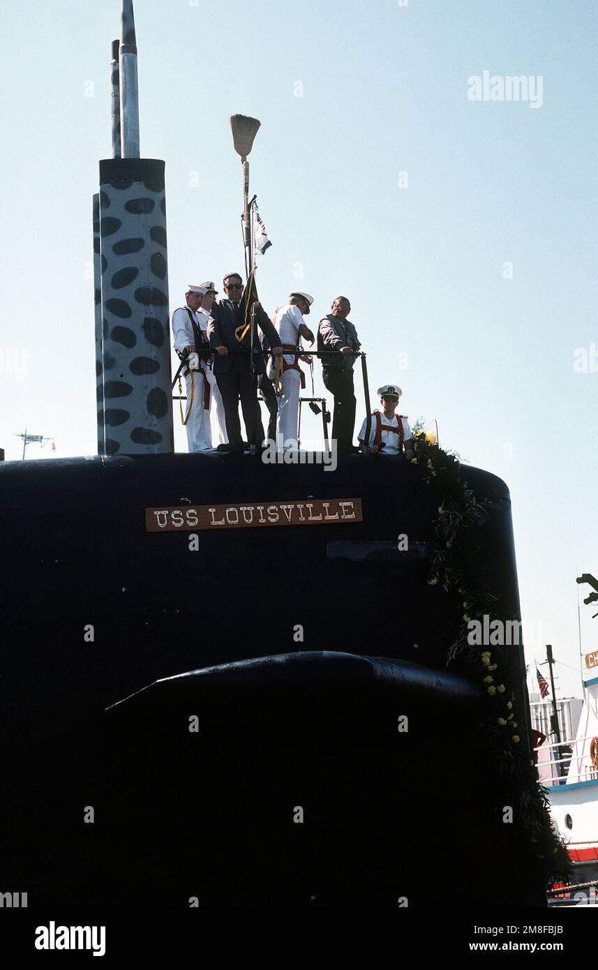 Crew members and civilians stand on the sail of the nuclear-powered ...