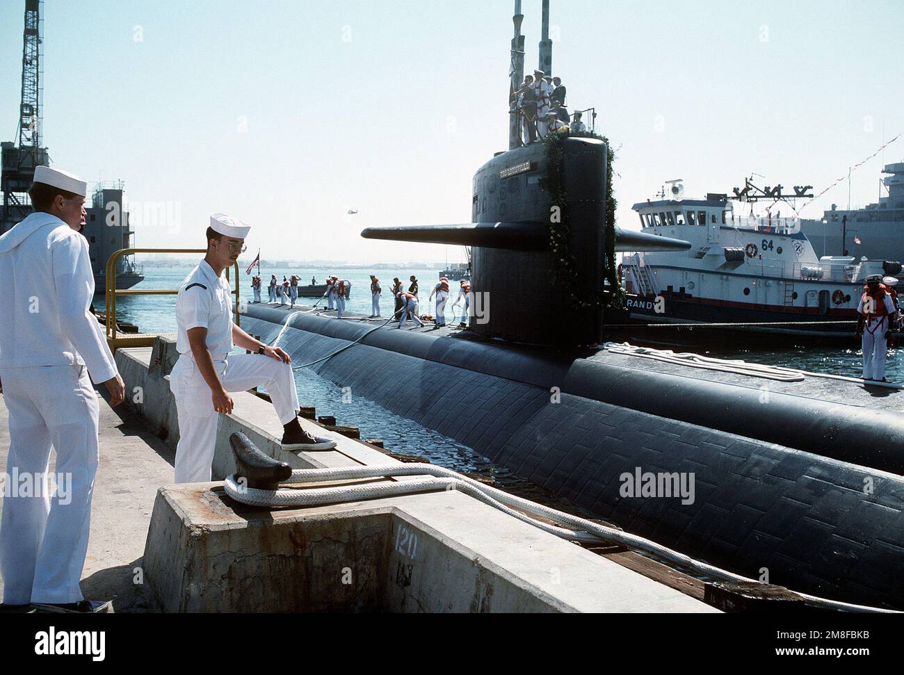 Line handlers stand by on the pier as a commercial tug moves the ...