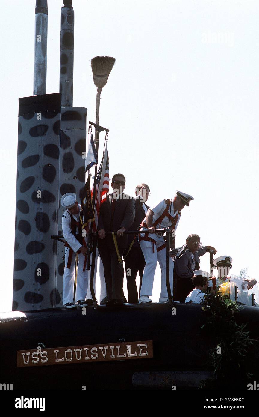Two civilian guests, a harbor pilot and several crew members stand atop ...