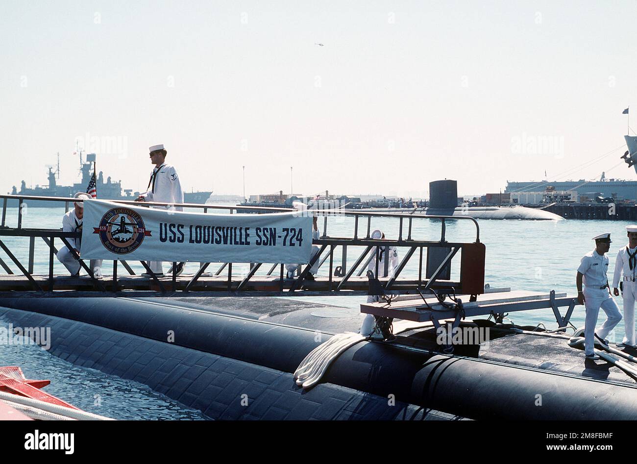 Sailors tie a banner onto the gangway placed between the pier and the ...