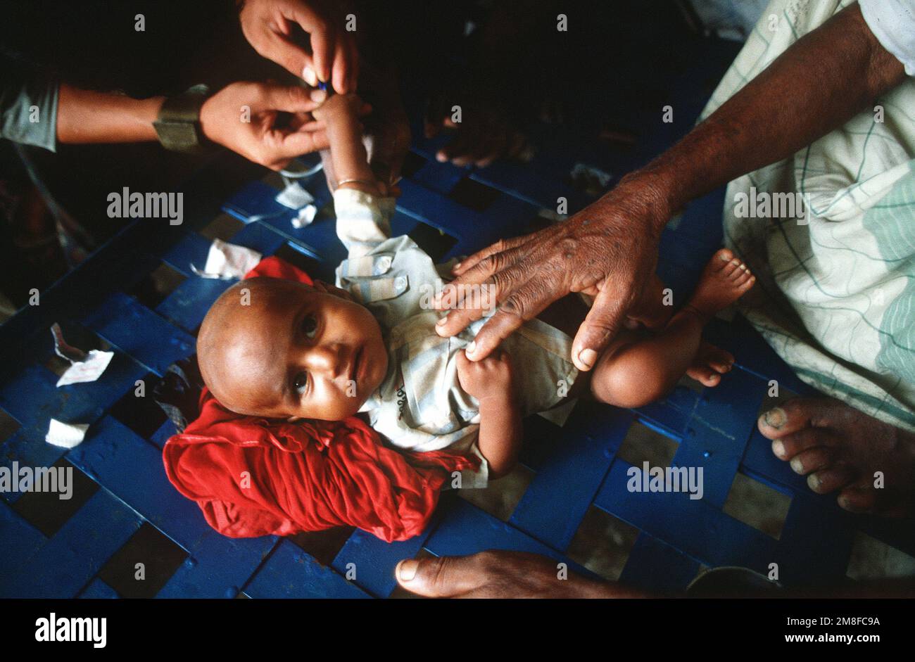 Members of a medical team examine a baby in the aftermath of a cyclone ...