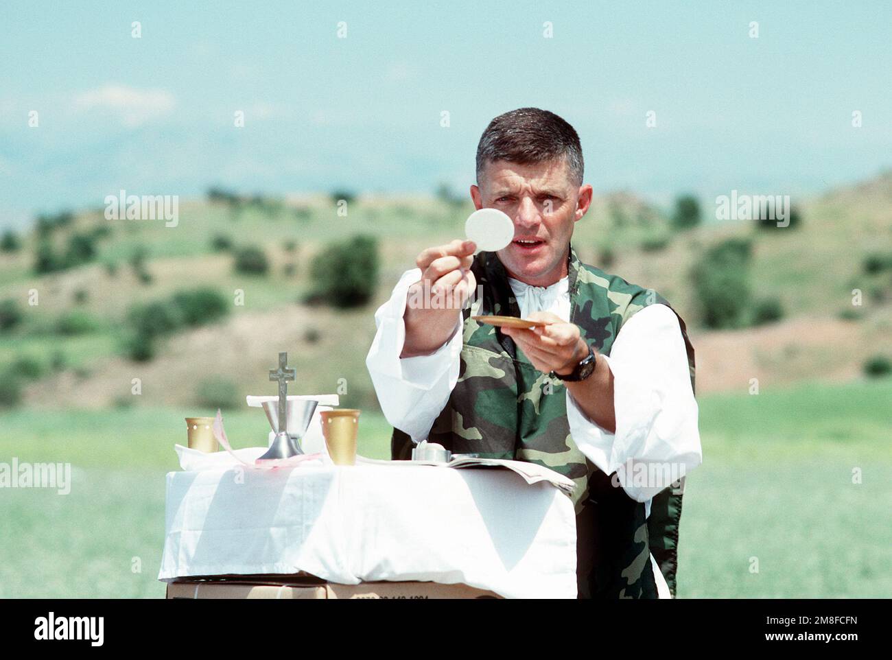 Chaplain (LT.) William D. Devine elevates the Eucharist as he ...
