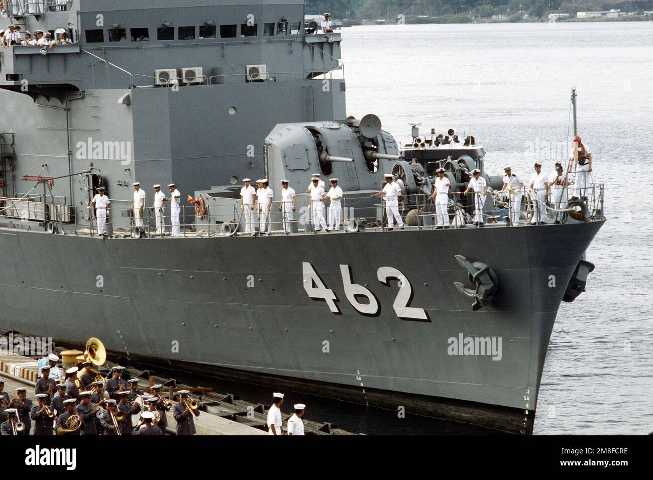 A band plays on the pier as the large harbor tug OPELIKA (YTB-798 ...